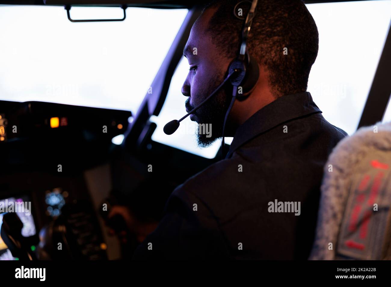 African american copilot flying airplane in cockpit with captain, using ...