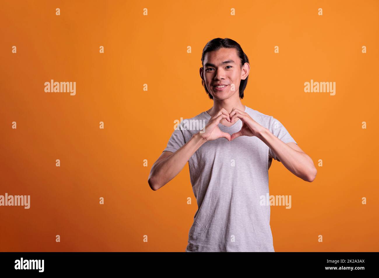 Young happy asian man showing heart shaped love gesture, romance symbol ...