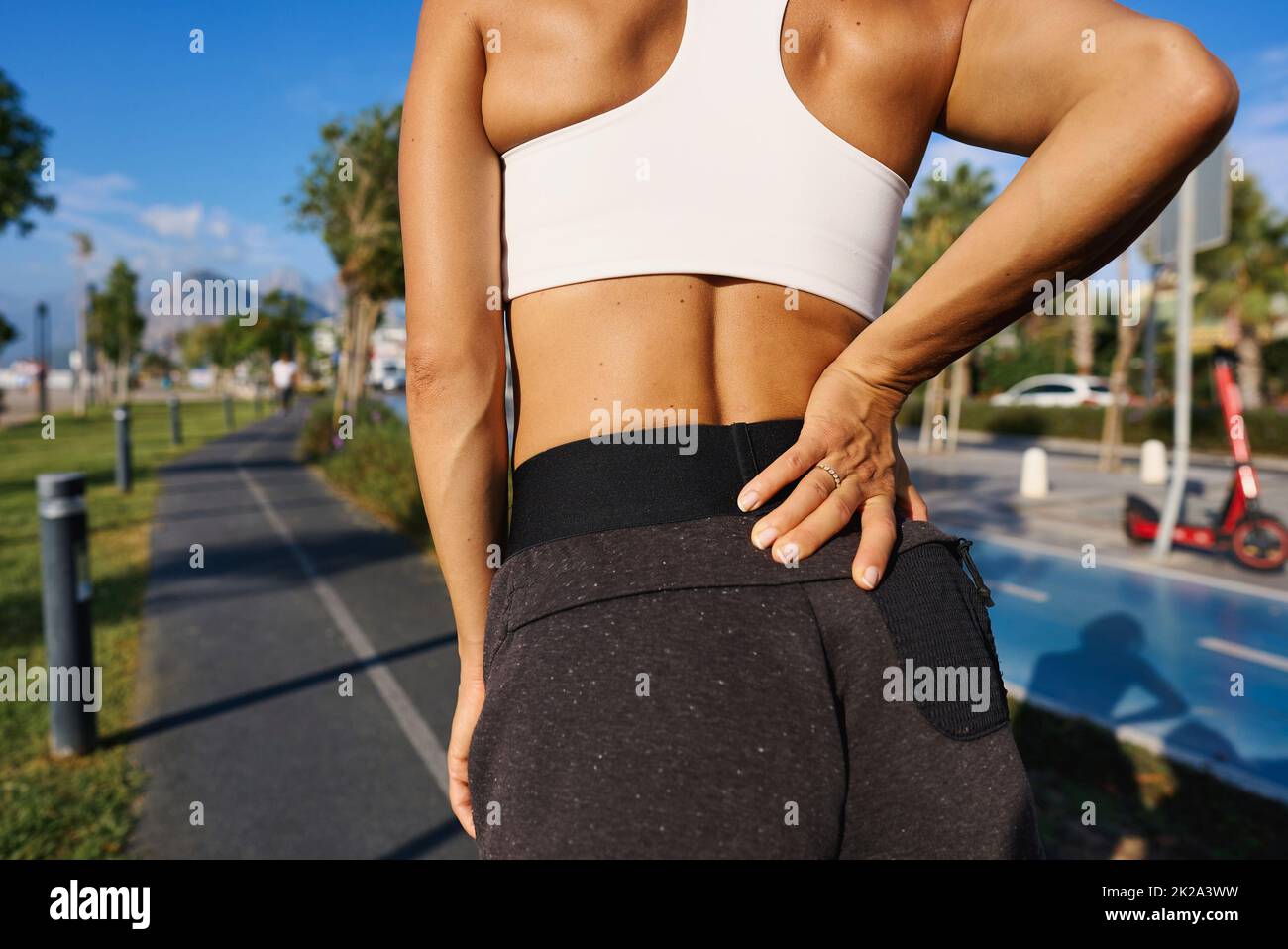 Athletic woman on running track touching hurt back with painful injury ...