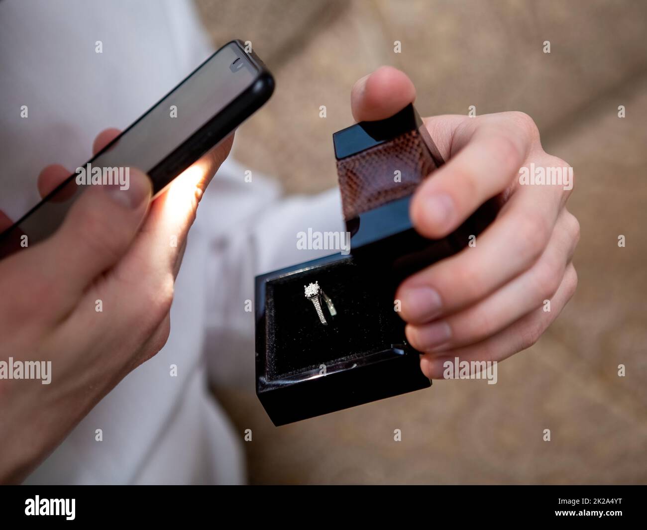A young man holds in his hands a jewelry box with a diamond ring inside ...