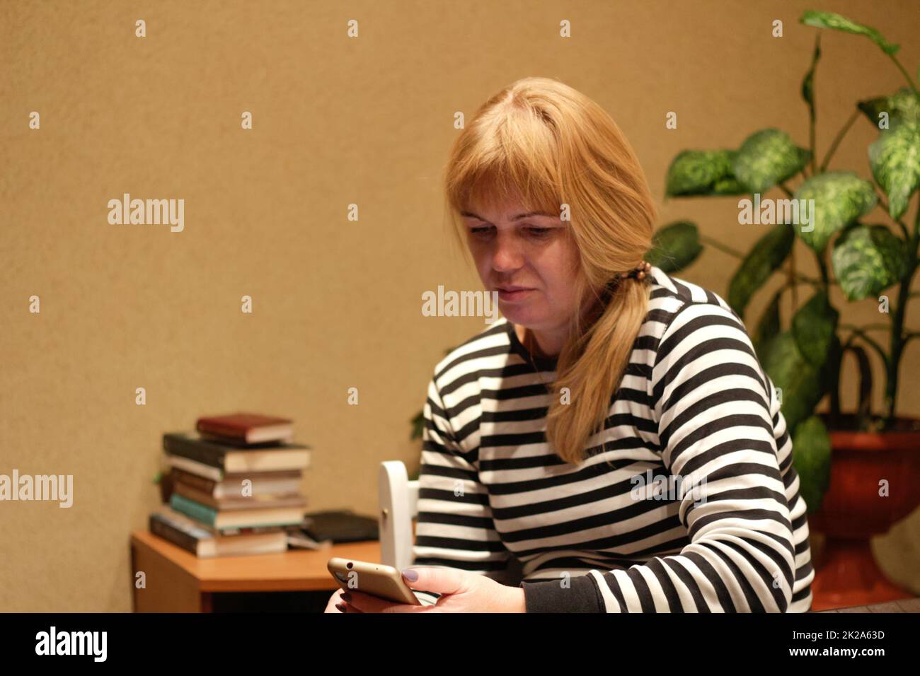 Defocus serious charming woman using smartphone while working at home ...