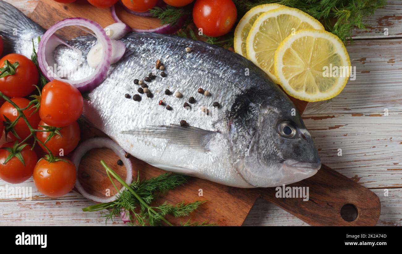 Raw fresh uncooked dorado or sea bream fish with lemon, herbs, cherry ...