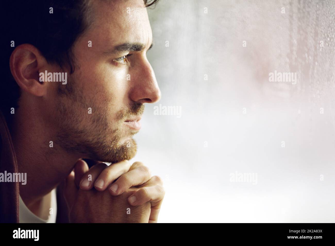 Thinking things over. A young man looking thoughtful as looks into the ...