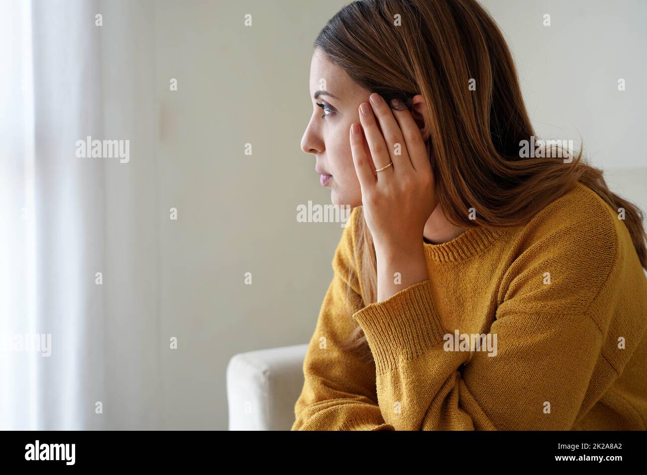 Portrait of sad lonely girl at home looking through window. Mental ...