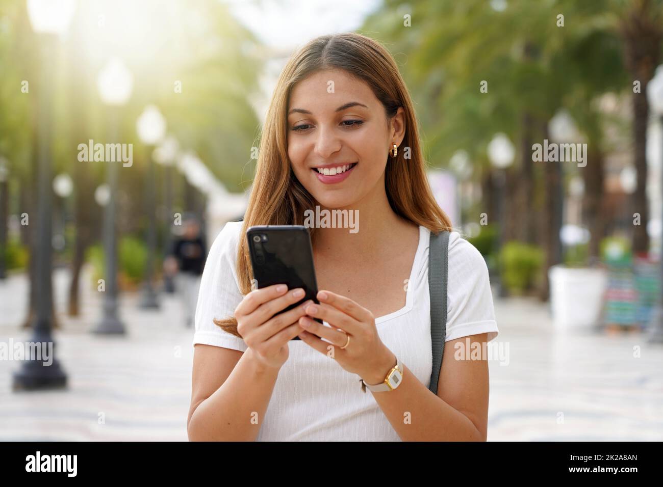 Close up of excited young woman watching her smartphone when walking in ...