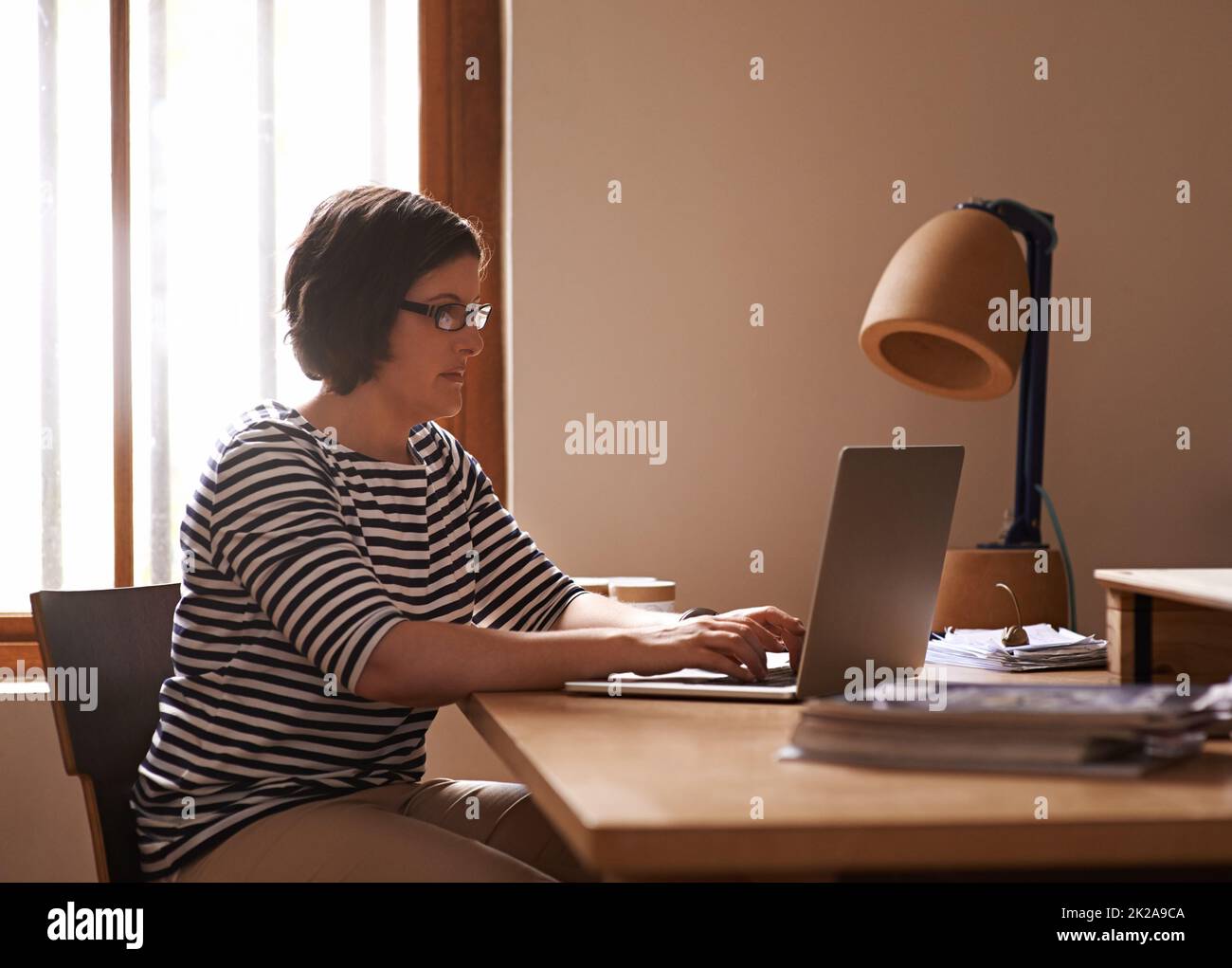 Morning admin. A cropped shot of a woman sitting at a desk in her home ...