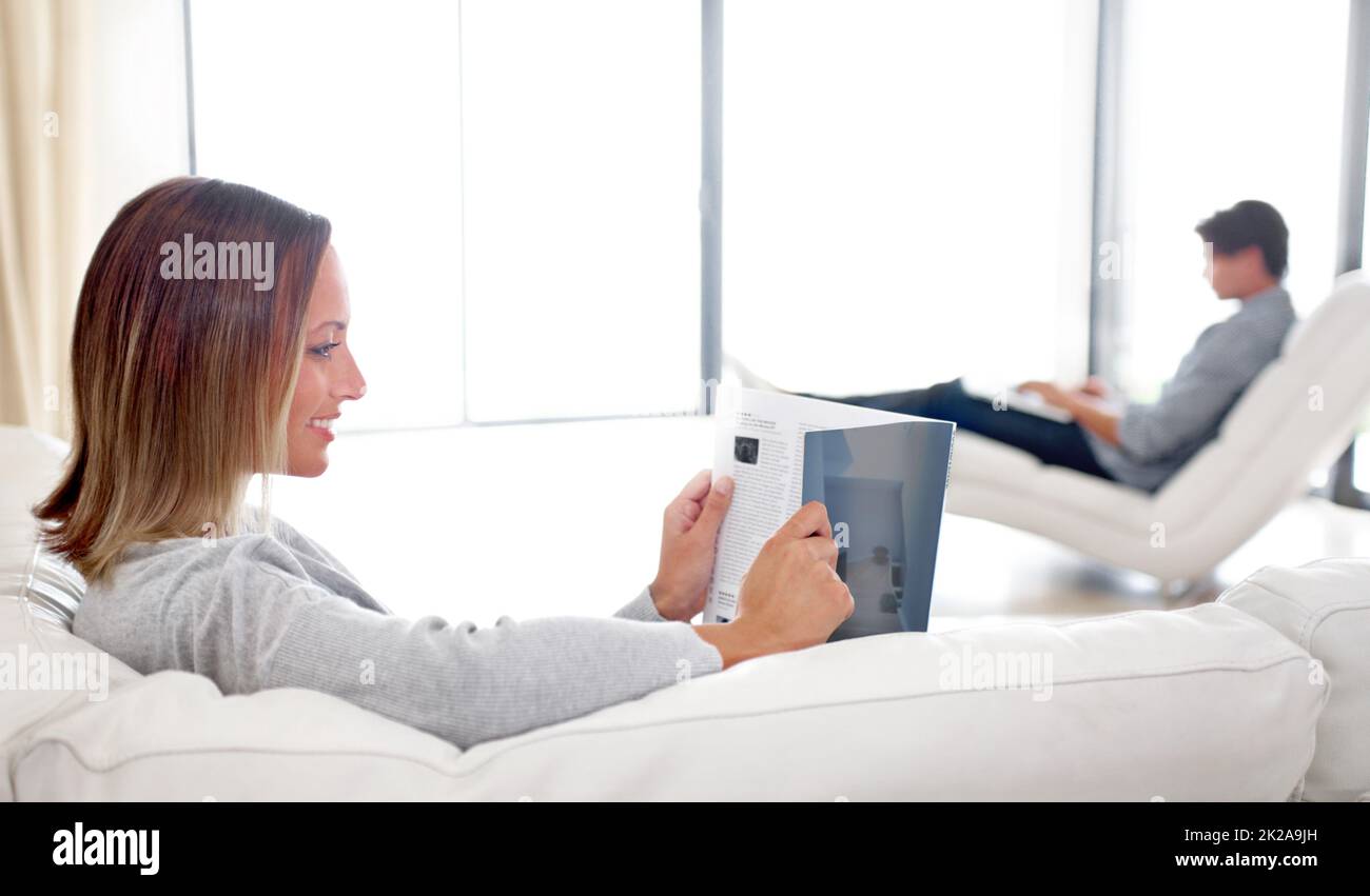 Catching up on the latest fashions. A young woman reading a magazine ...