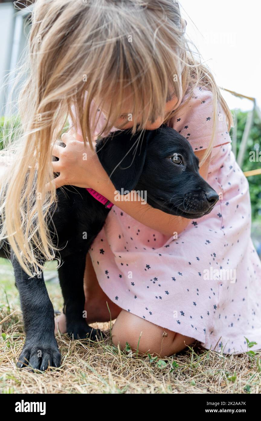 Bond between a puppy and child - toddler girl hugging and kissing a ...