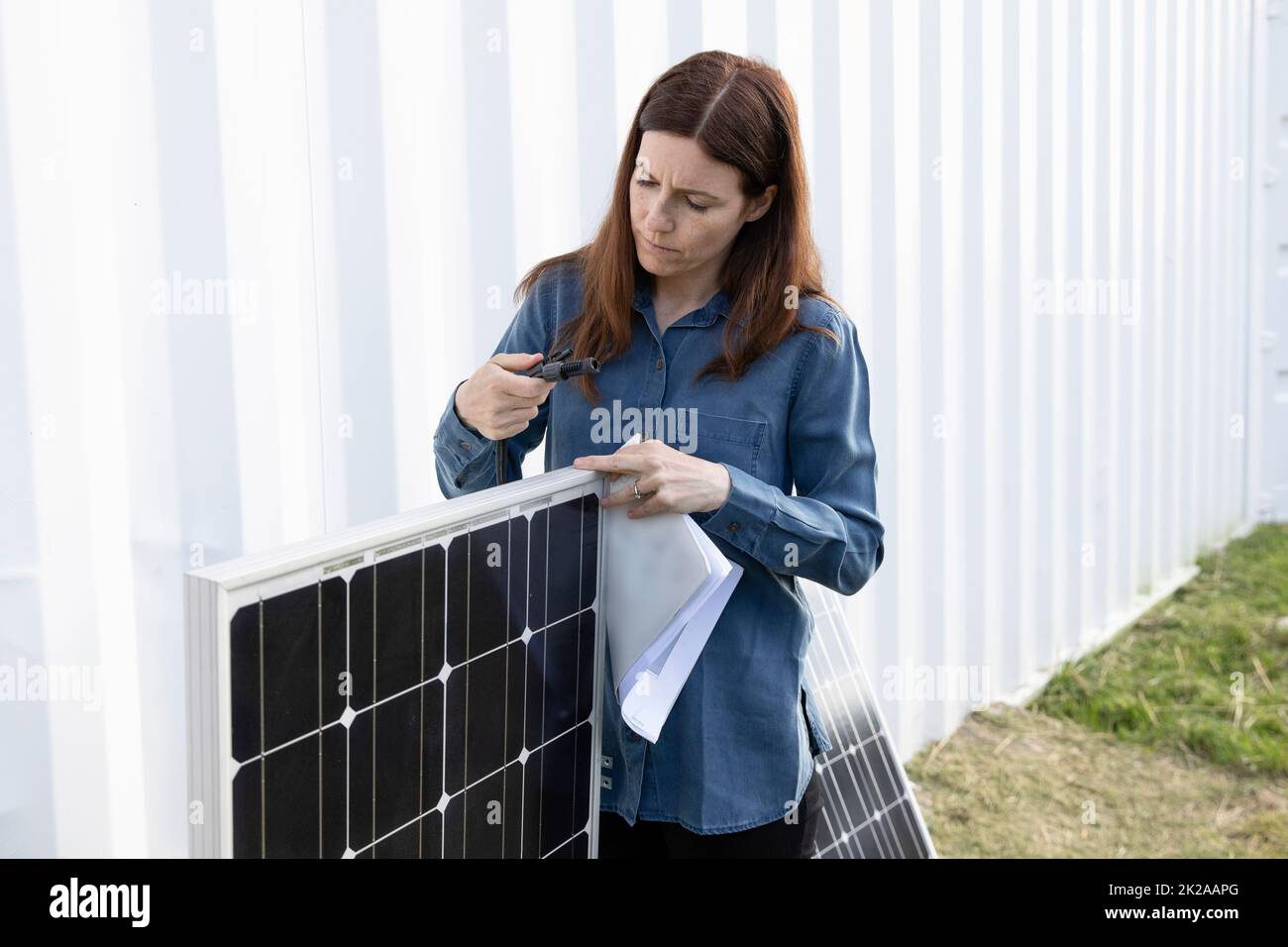 Woman fitting solar panels to container home Stock Photo - Alamy