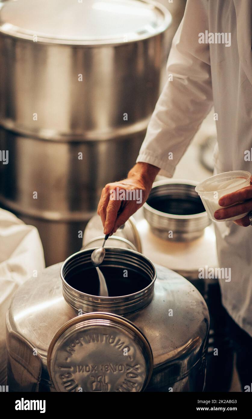 man in lab coat using spoon to pour white powder into stainless steel ...