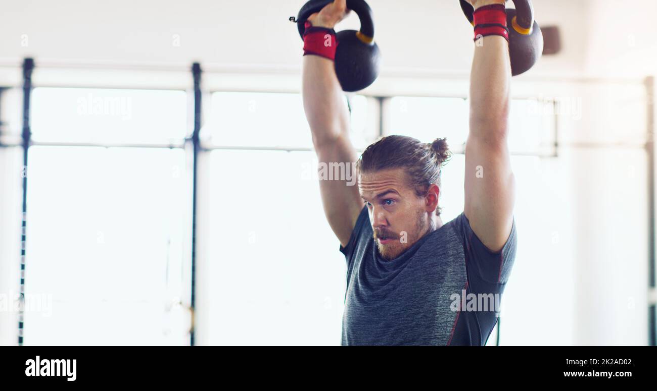 Keep lifting for arms of steel. Shot of a young man working out with ...