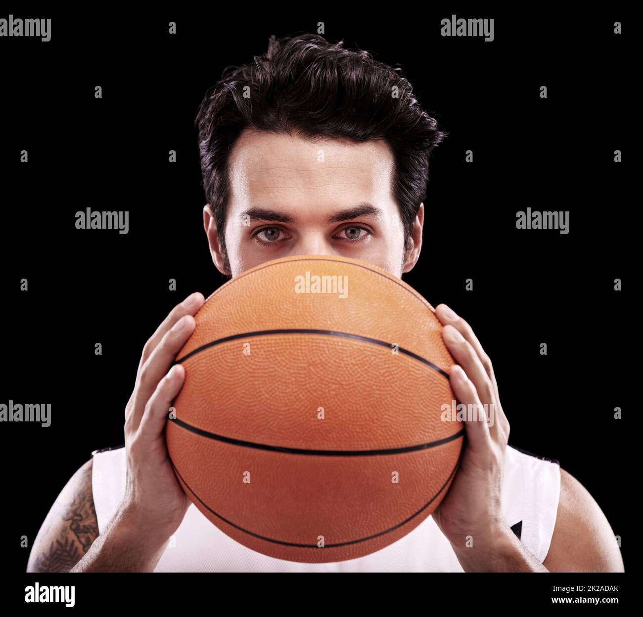 I came to play. A young man holding a basketball against a black ...