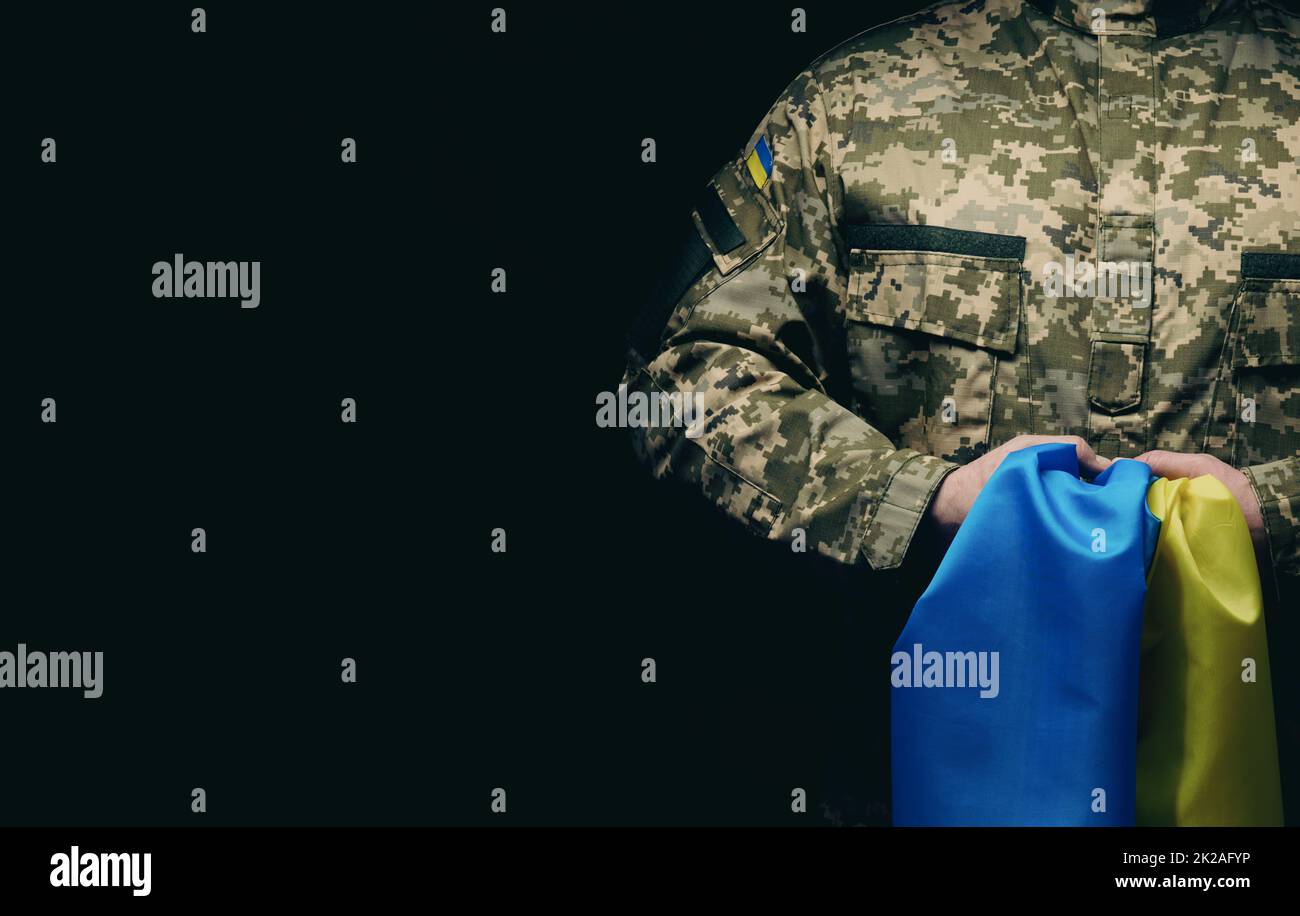 soldier of the Ukrainian armed forces stands with a blue-yellow flag of ...