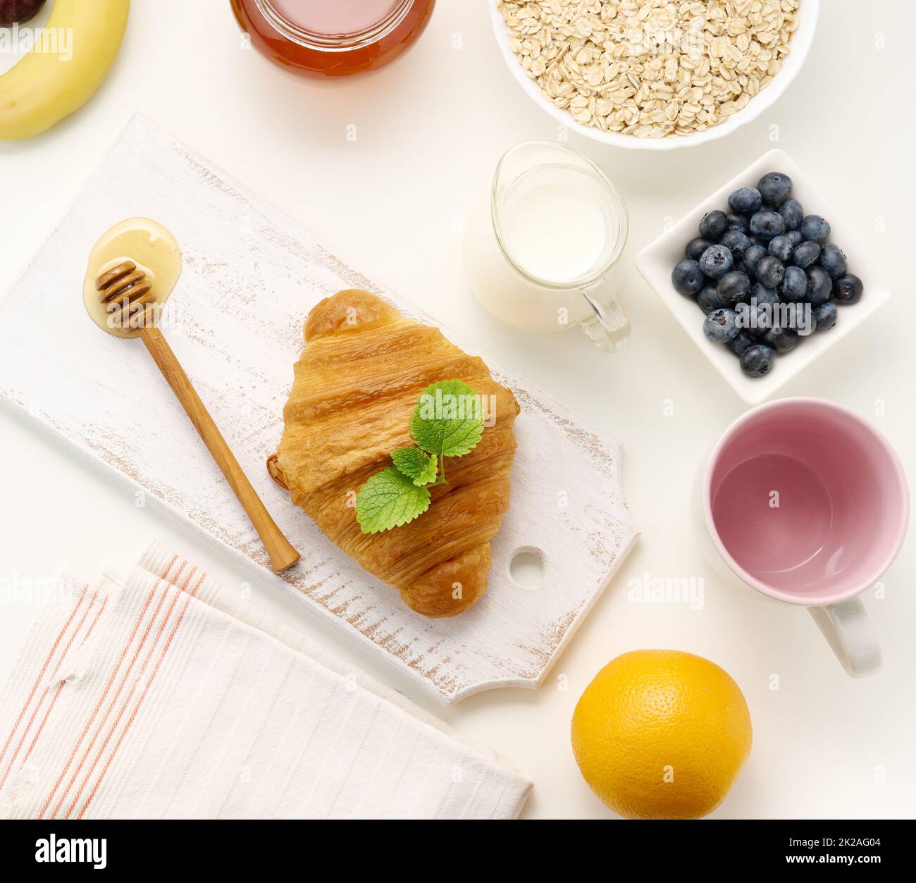 Morning breakfast, raw oatmeal flakes in a ceramic plate, milk in a ...