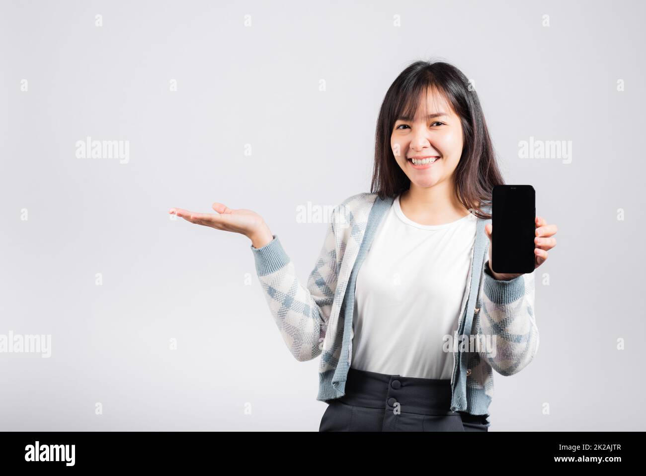 Woman excited holding mobile phone blank screen presenting product with ...