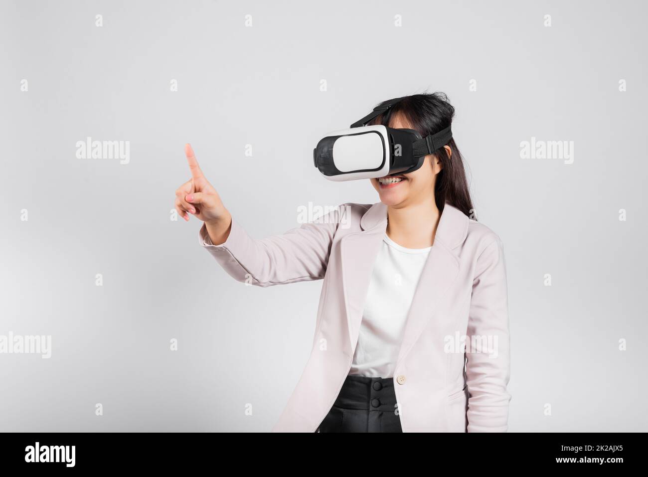 Smiling woman confidence wearing VR headset device touching air during ...
