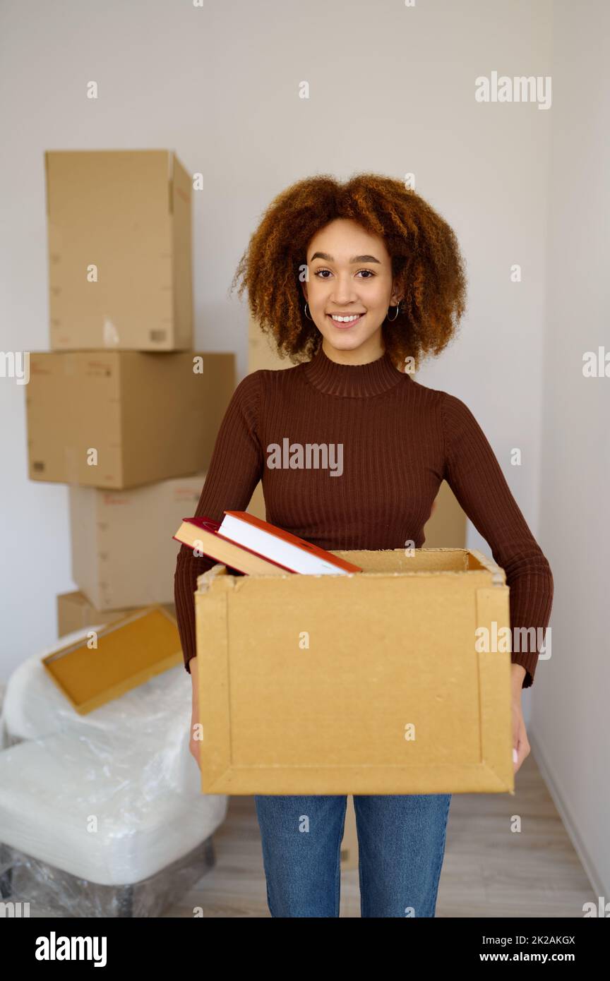 Young woman carrying cardboard box during relocation Stock Photo - Alamy