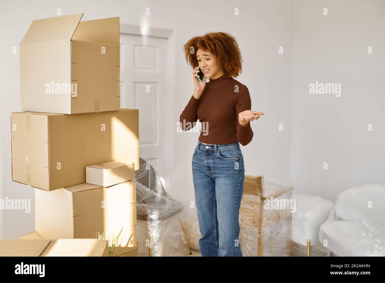 Young woman talking phone among cardboard boxes Stock Photo - Alamy