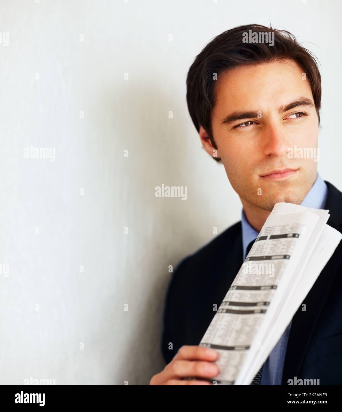 Thoughtful young business man holding a newspaper. Portrait of a ...
