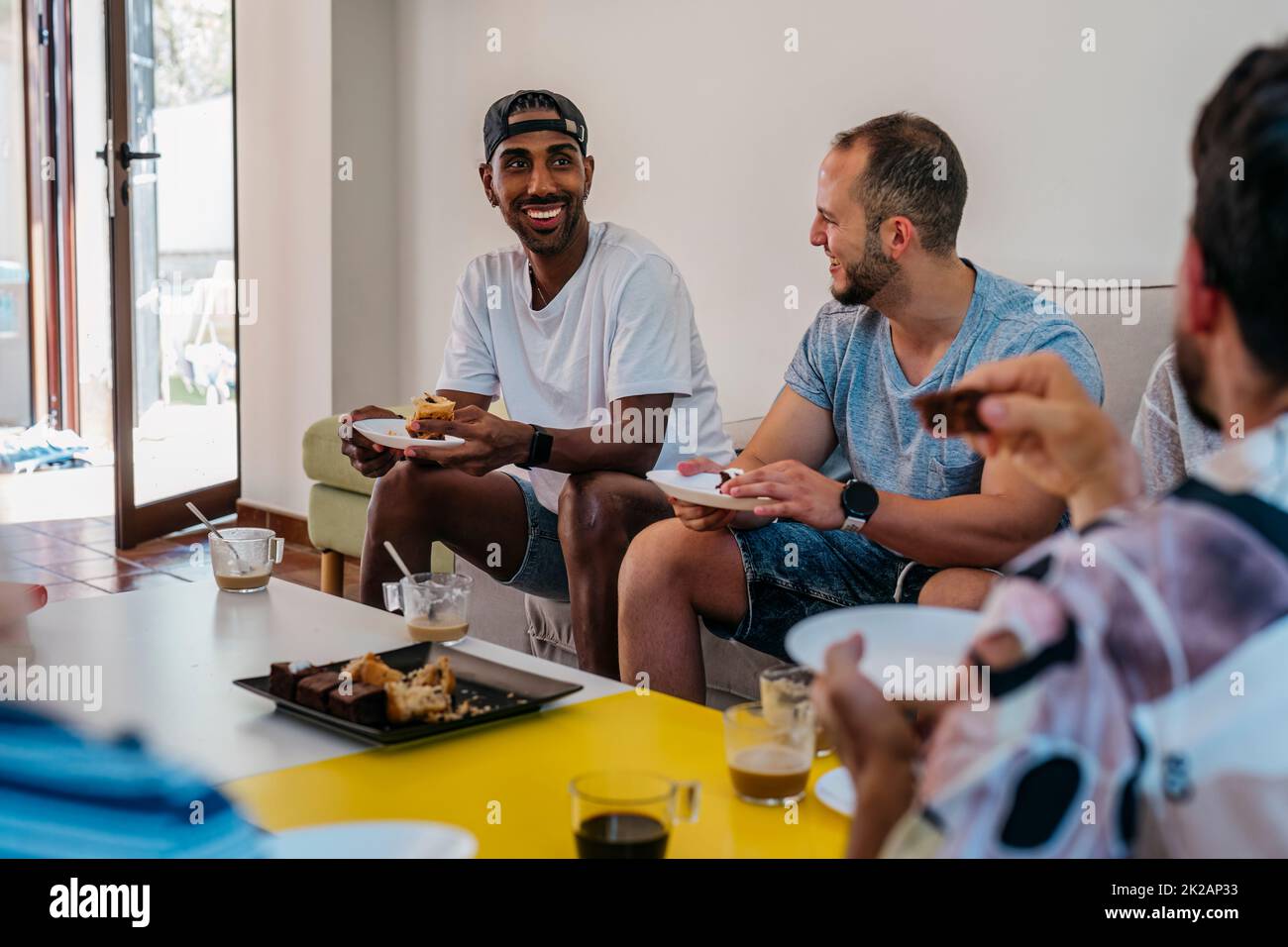 african american man smiles while eating pastries at a gathering of ...