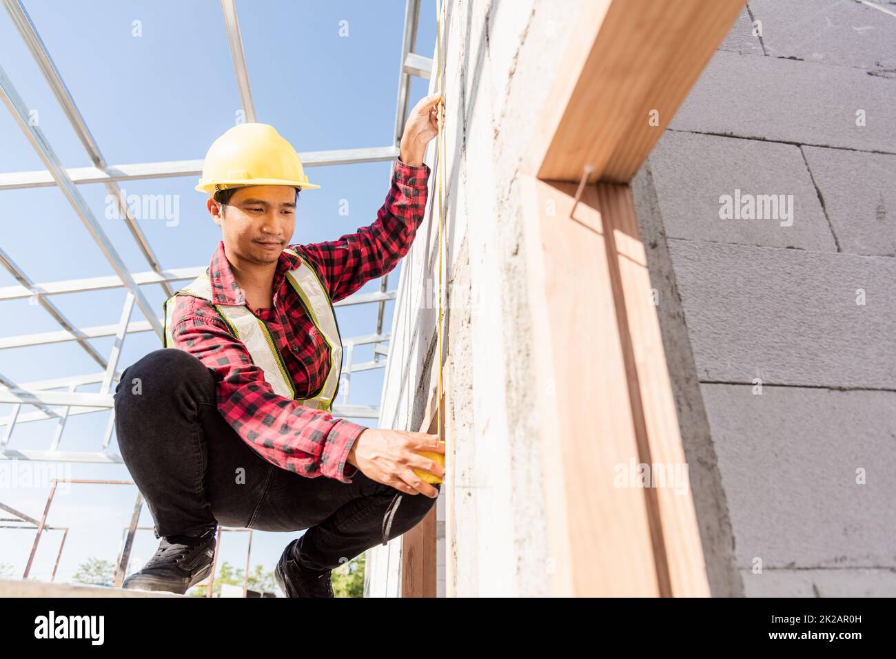 Construction worker or contractor man using measuring tape checking ...