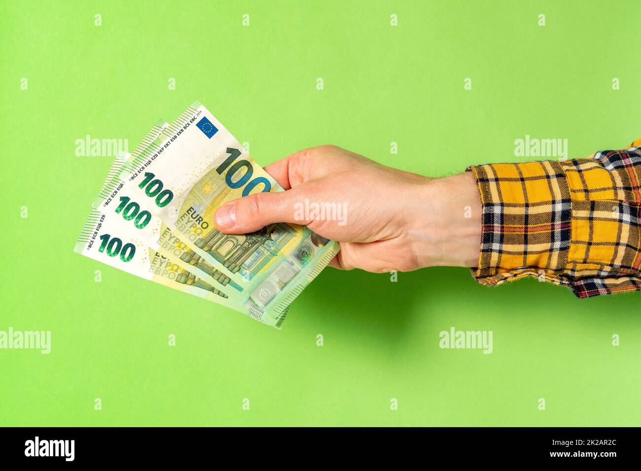 Hand holding euro banknotes on a green background Stock Photo - Alamy
