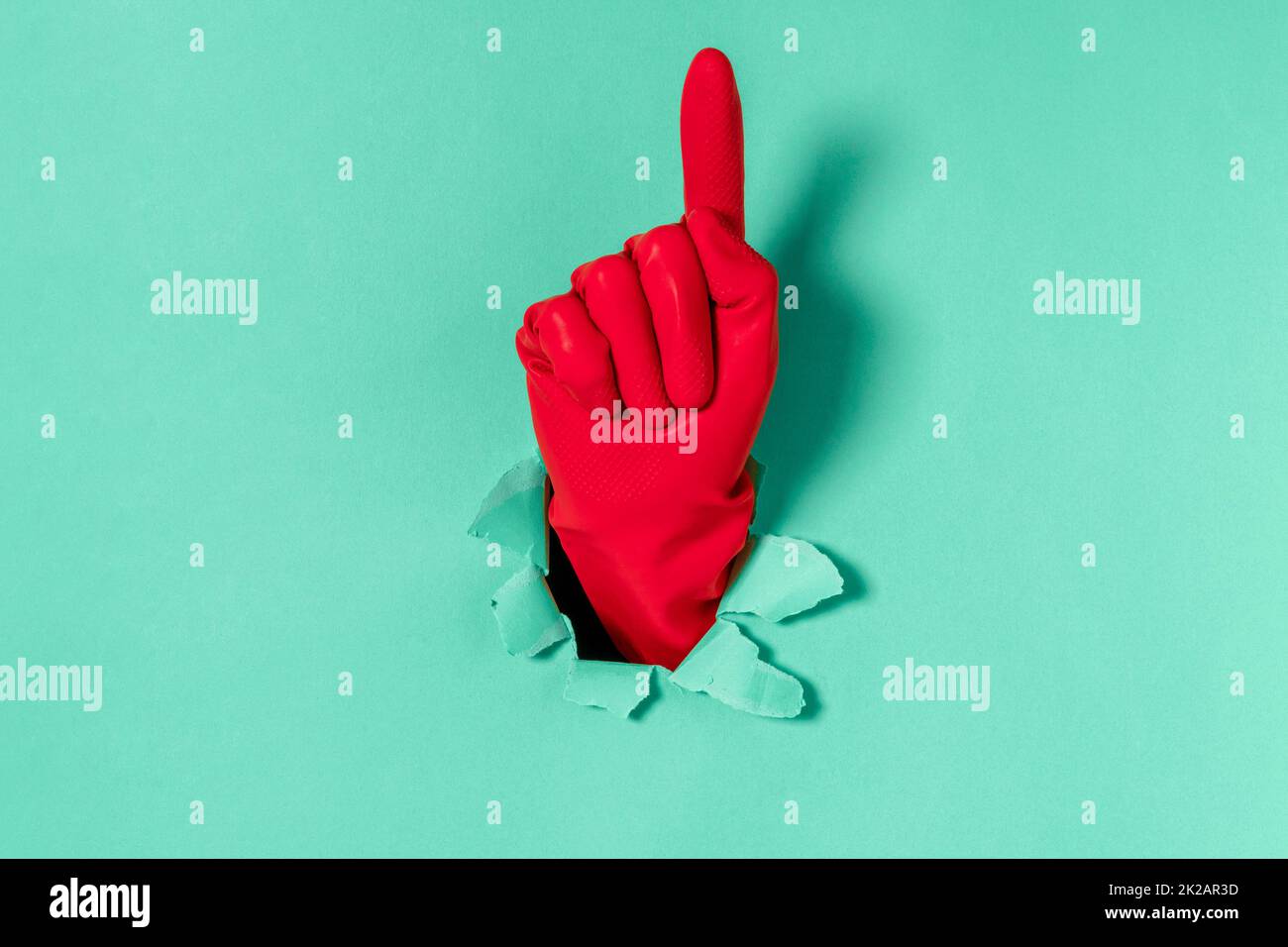 Hand sticking out of a torn hole in a blue paper background, attention ...