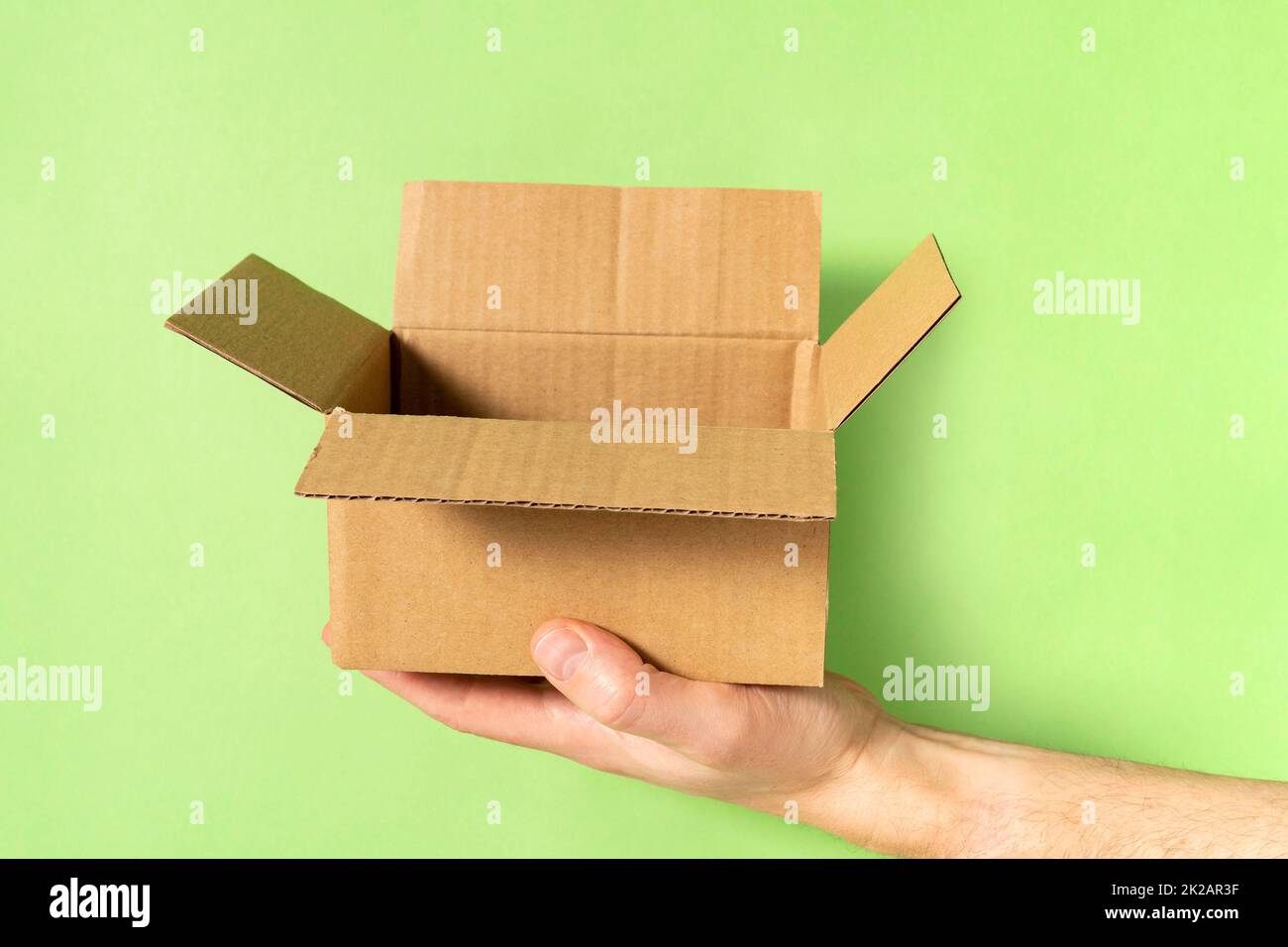 Hand holding open brown paper box Stock Photo - Alamy