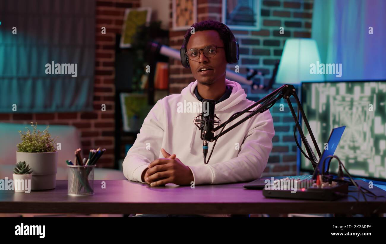 African american online radio host reading fan mail from laptop talking ...