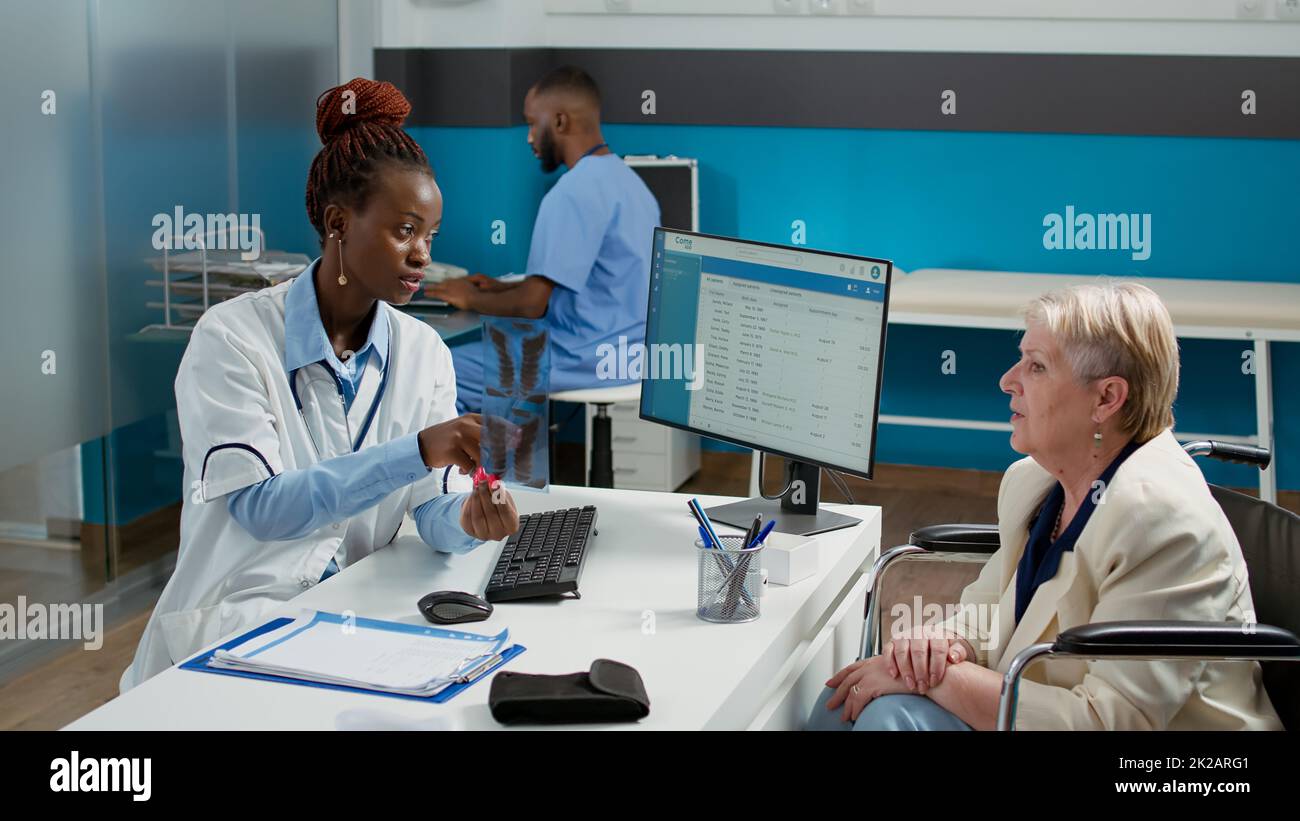 Wheelchair user and doctor analyzing radiography results at medical ...