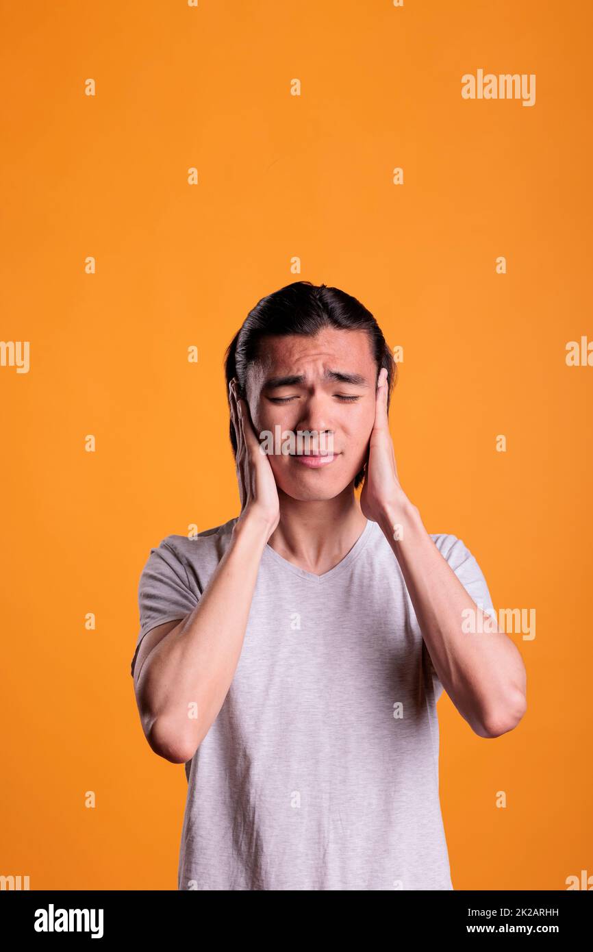 Young asian man covering ears with hands, hear no evil, three wise ...