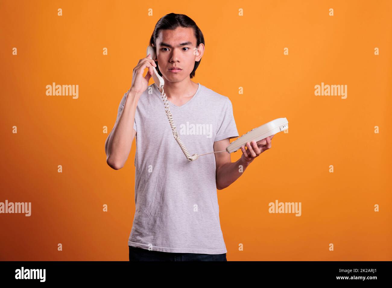 Young scared man talking on landline phone. Confused asian teen ...
