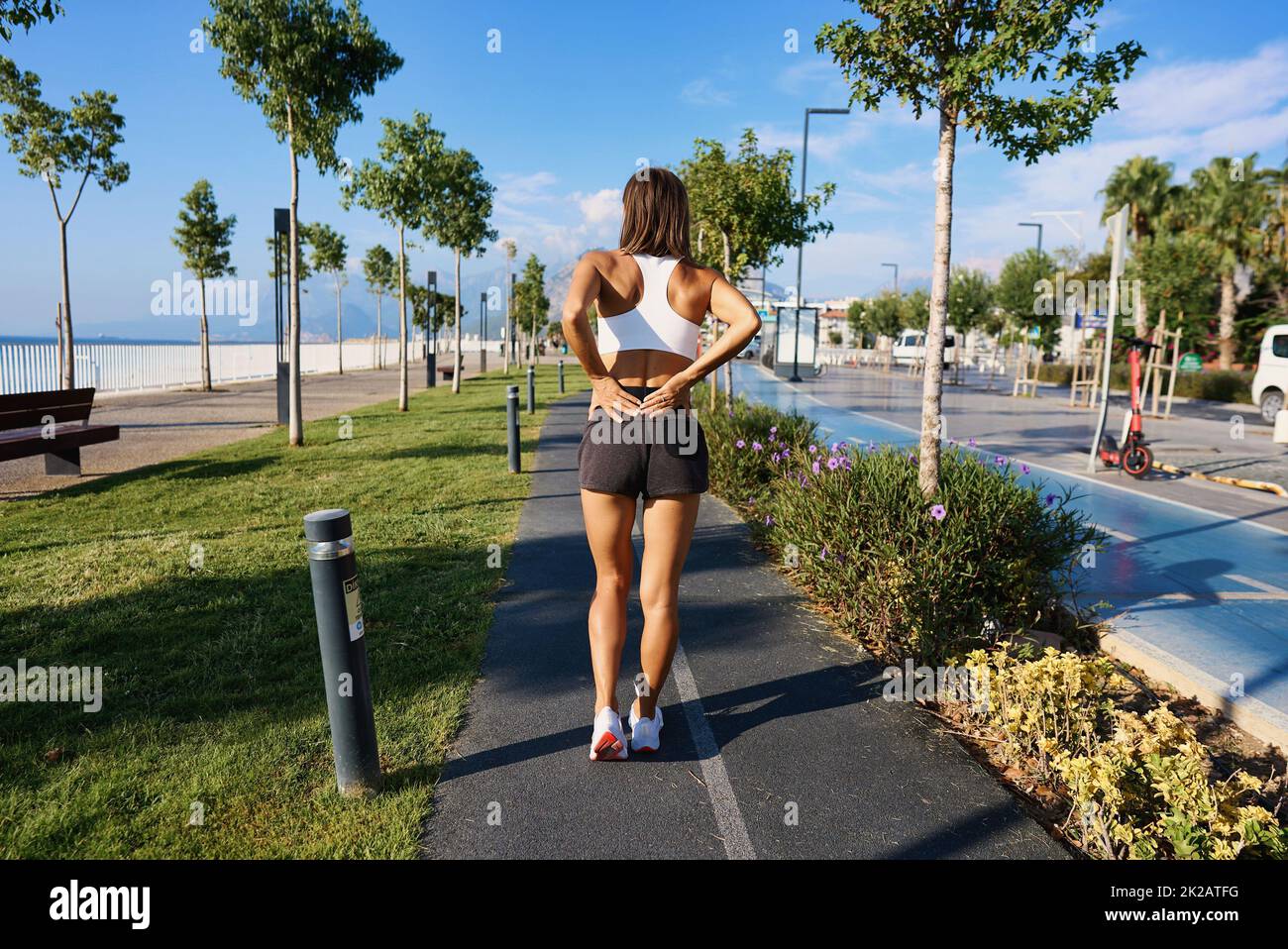Athletic woman on running track touching hurt back with painful injury ...