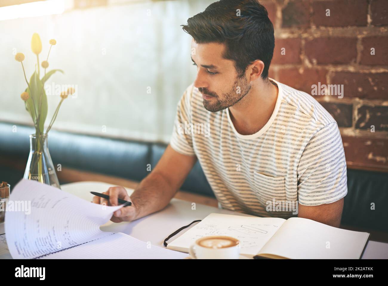 Business with the pleasure of coffee. A young man doing some work in a ...