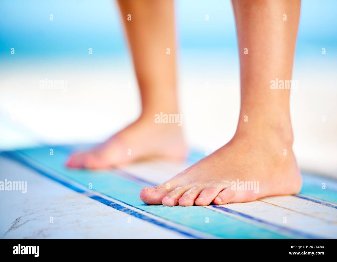 Surfing is my life. A close up of feet on a surfboard on the beach ...