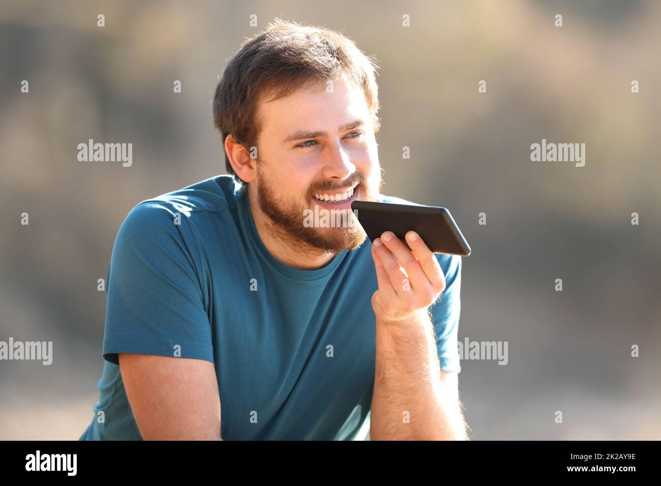 Happy man using voice recognition on cellphone outdoors Stock Photo - Alamy