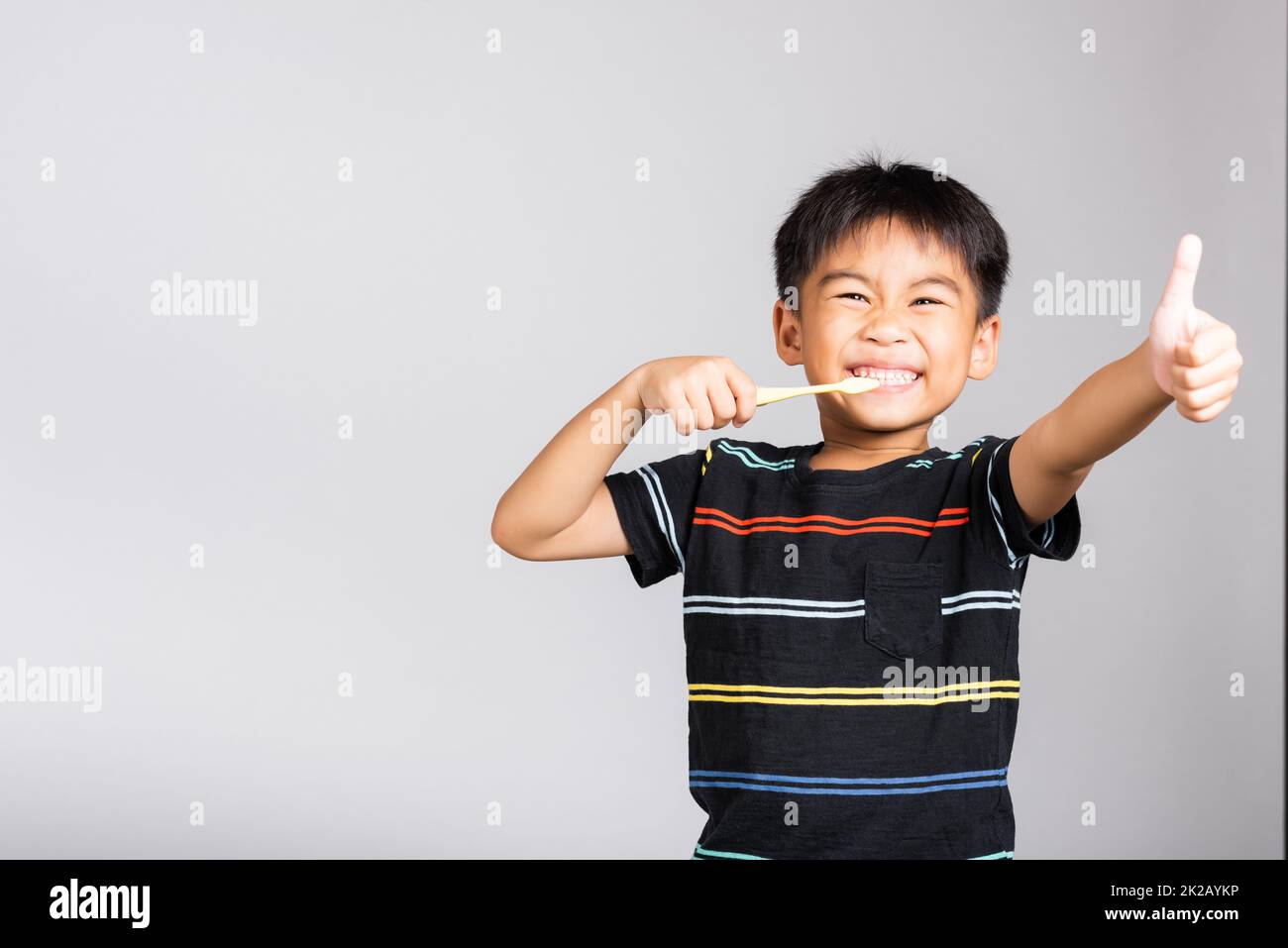 Little cute kid boy 5-6 years old smile brushing teeth and show thumb ...
