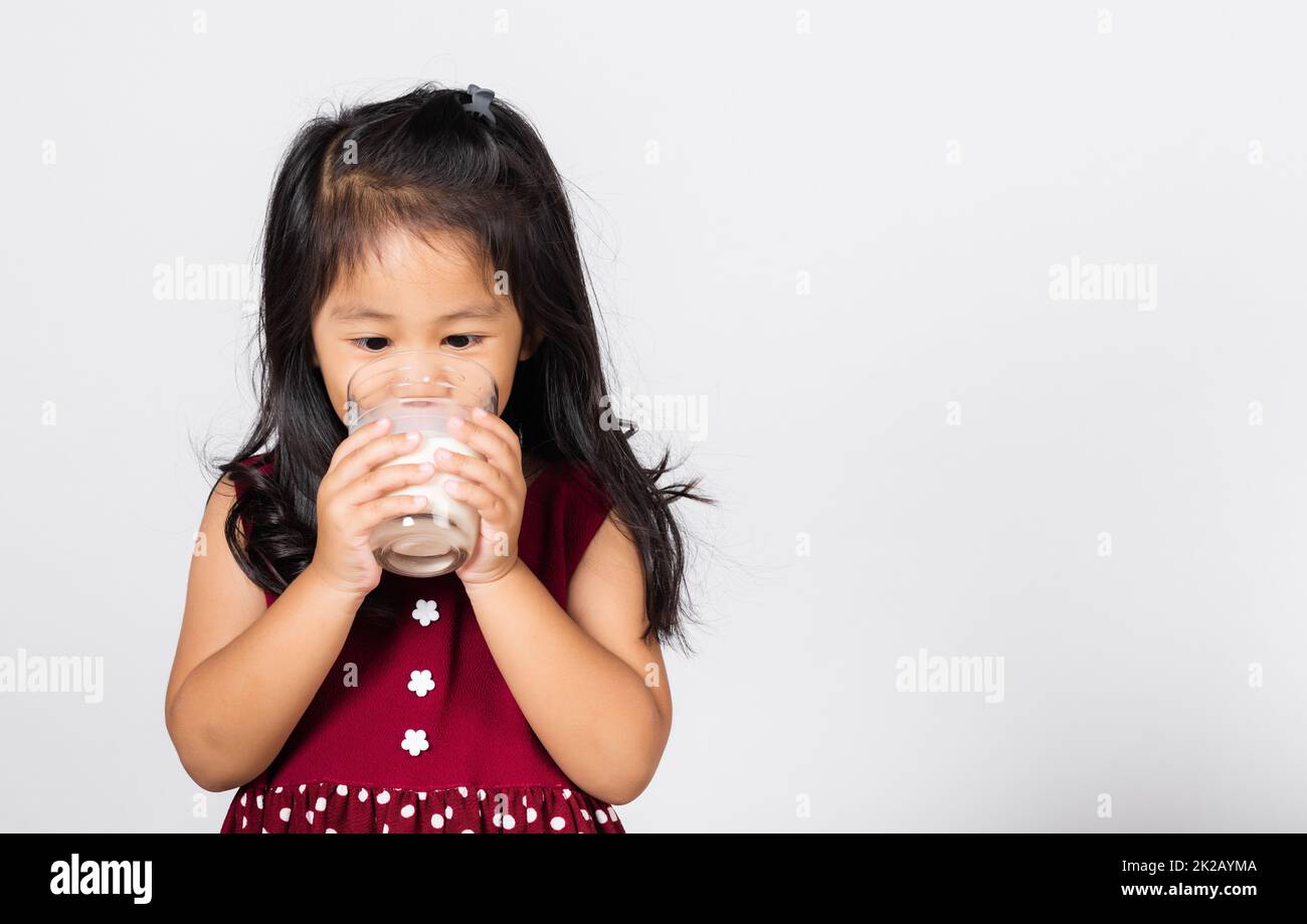 Little cute kid girl 3-4 years old smile holding milk glass he drinking ...