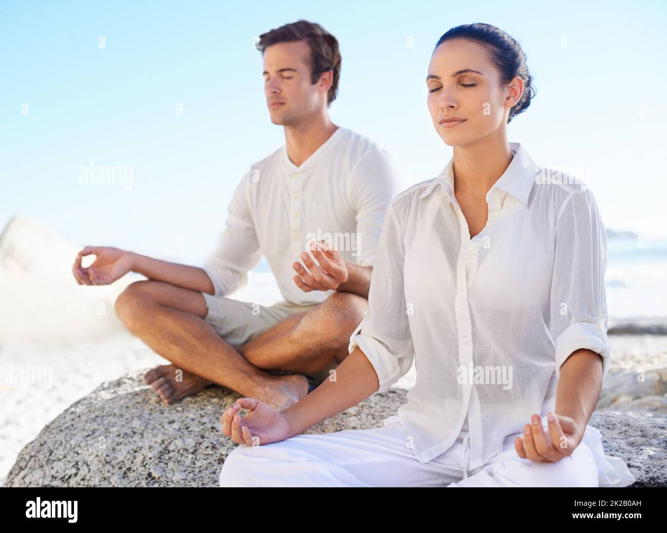 Peace in nature. A young couple performing a relaxing yoga routine ...