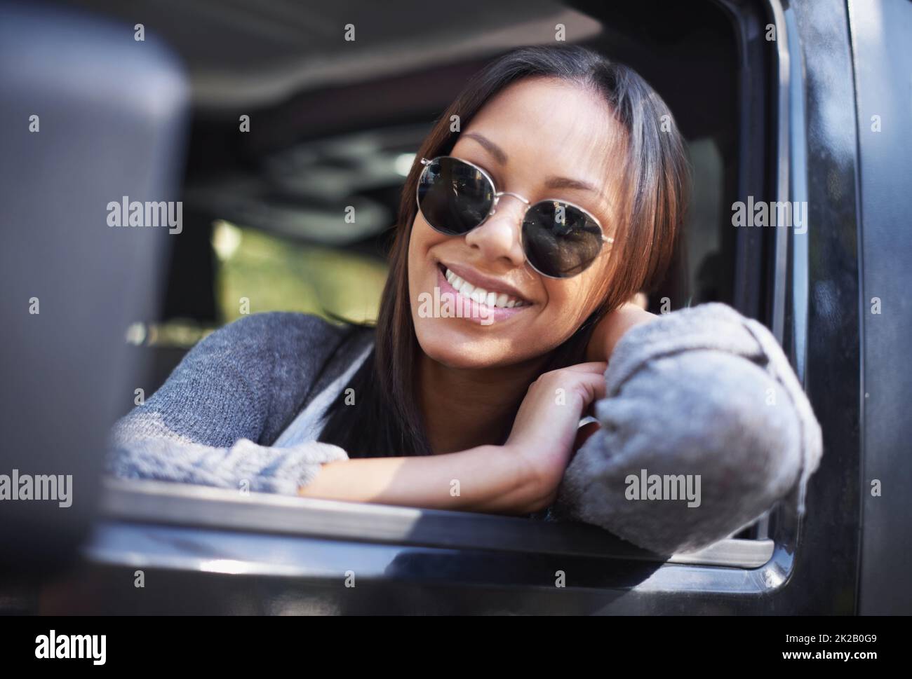 Just enjoying the ride. A young ethnic woman smiling while looking out ...