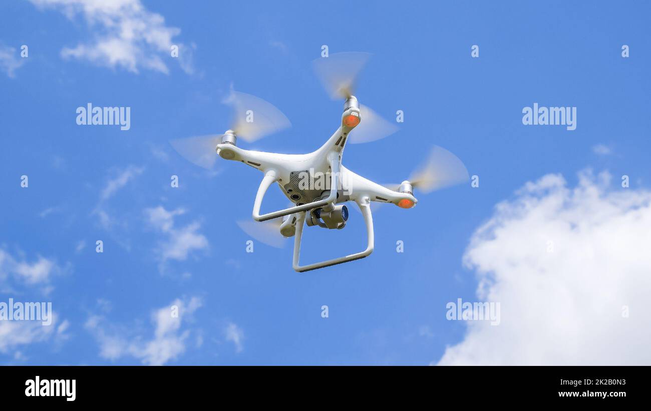 Drone DJI Phantom 4 in flight. Quadrocopter against the blue sky with ...