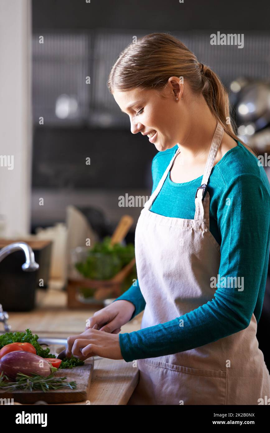 Happily chopping away. an attractive young woman chopping vegetables in ...
