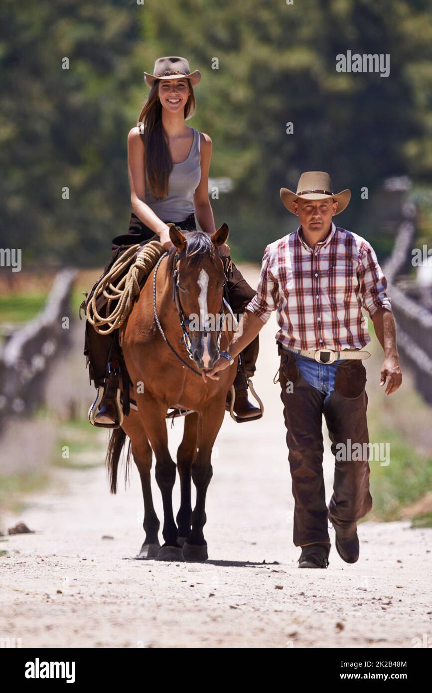 Riding 101. An attractive young cowgirl riding a horse on a ranch while ...