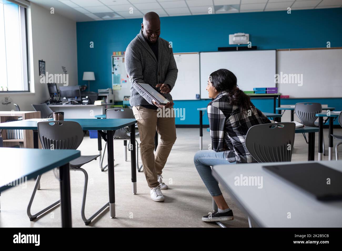 Teacher showing student tablet in class Stock Photo - Alamy
