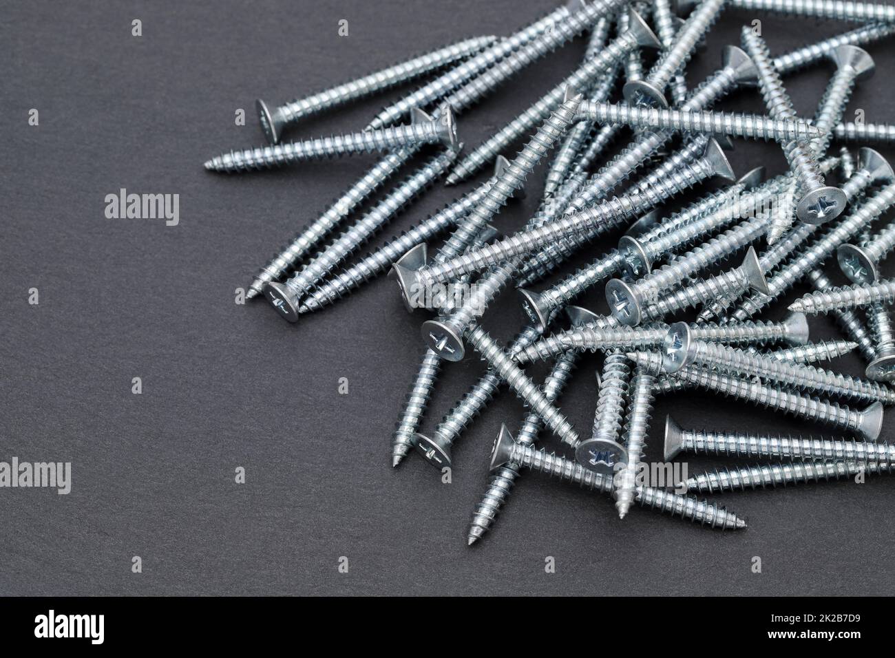 Pile of silver metallic tapping screws on black background Stock Photo ...