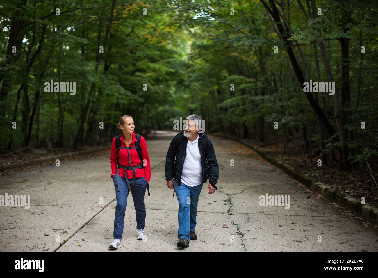 Active handsome senior walking, hiking outdoors on a forest path ...