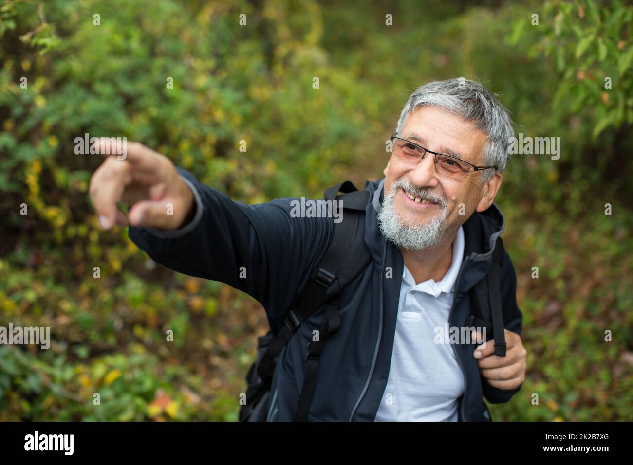 Active handsome senior man stoping for a moment while nordic walking ...
