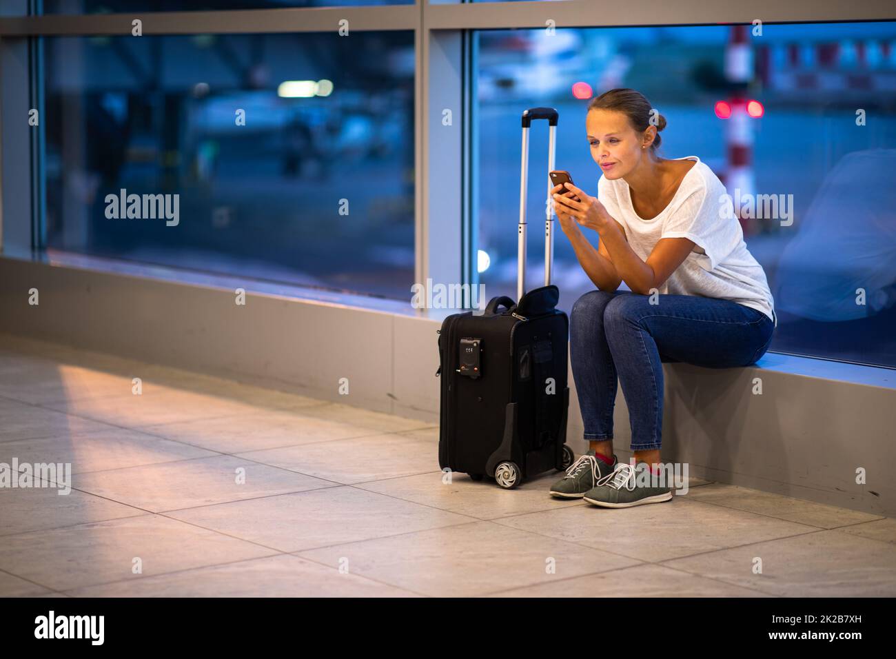 Young woman with her luggage at an international airport, before going ...