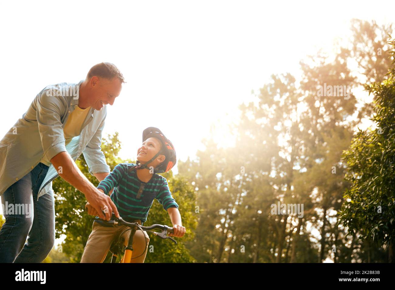 Adult helping a young person how to ride a bike hi-res stock ...