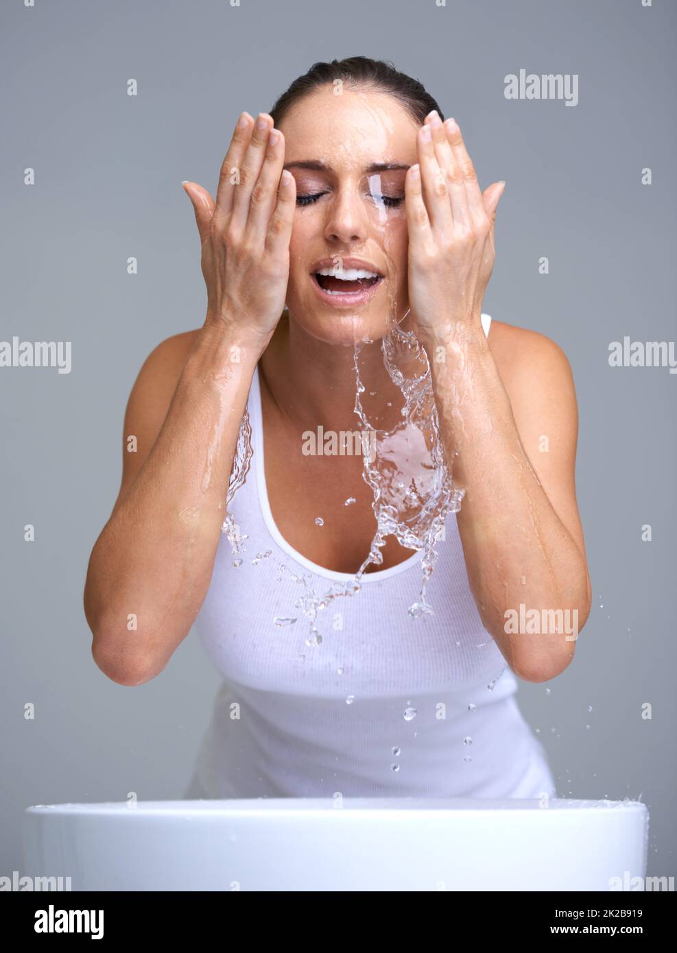 A good way to wake up. An attractive young woman washing her face Stock ...